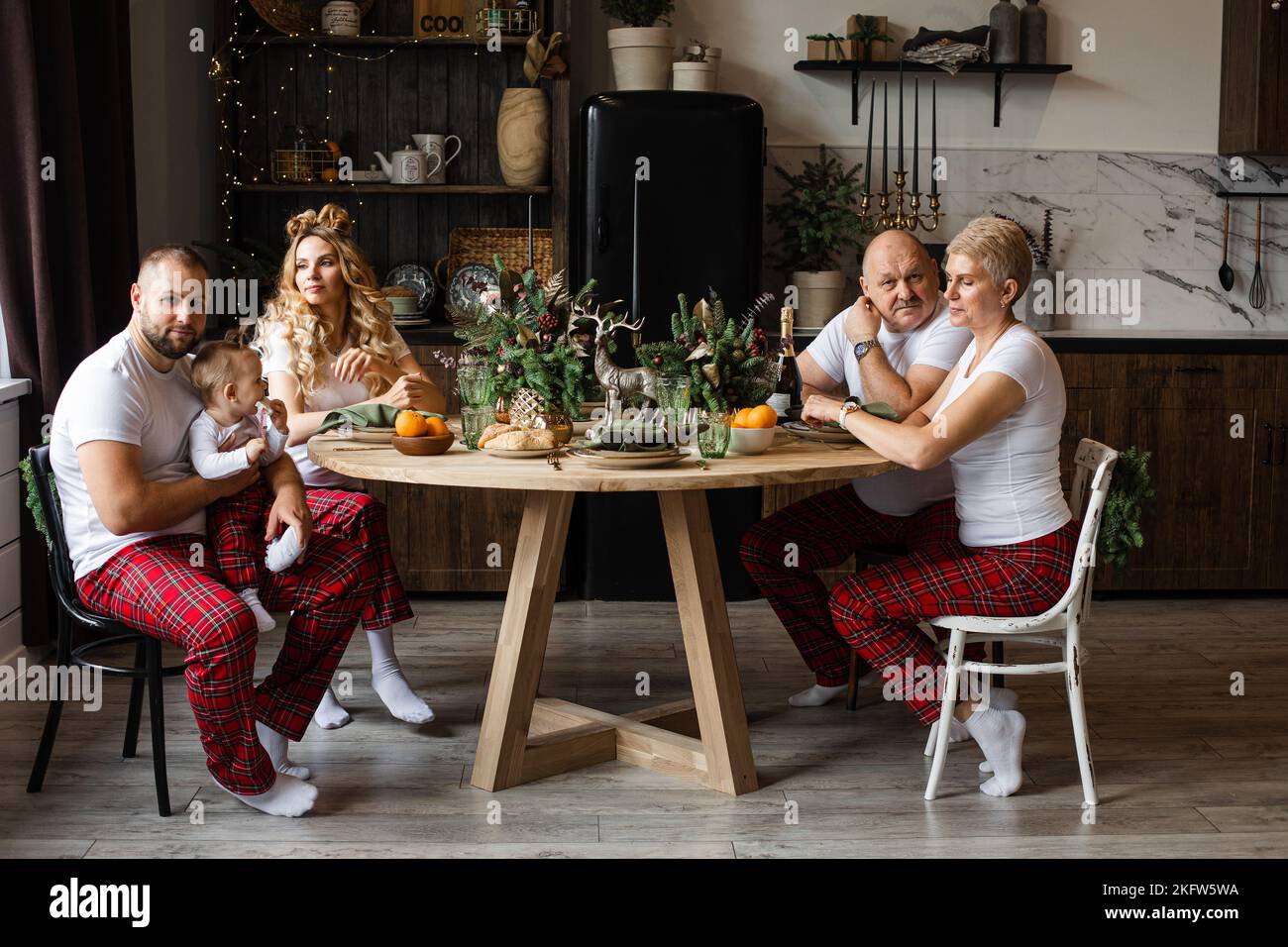 Child, parents and grandparents sitting at the table in the morning ...