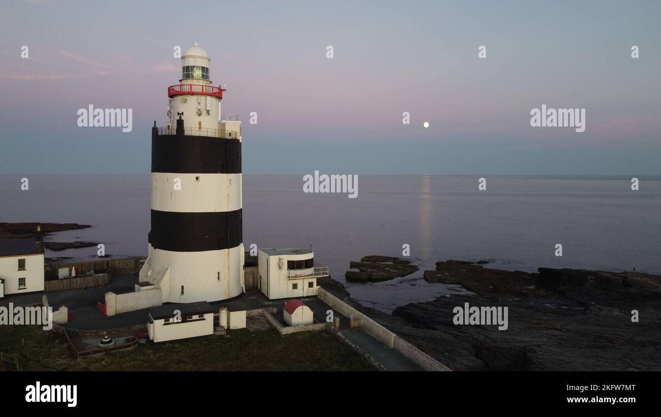 A scenic shot of a coastal lighthouse with the pink evening sky on the ...