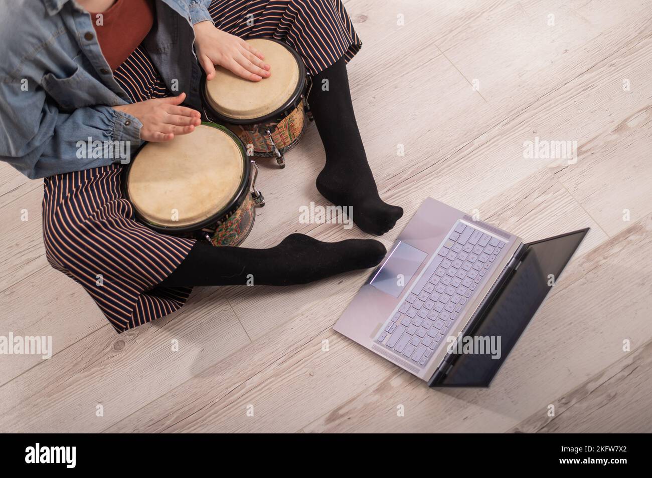 A faceless woman sits on the floor at home and watches educational ...