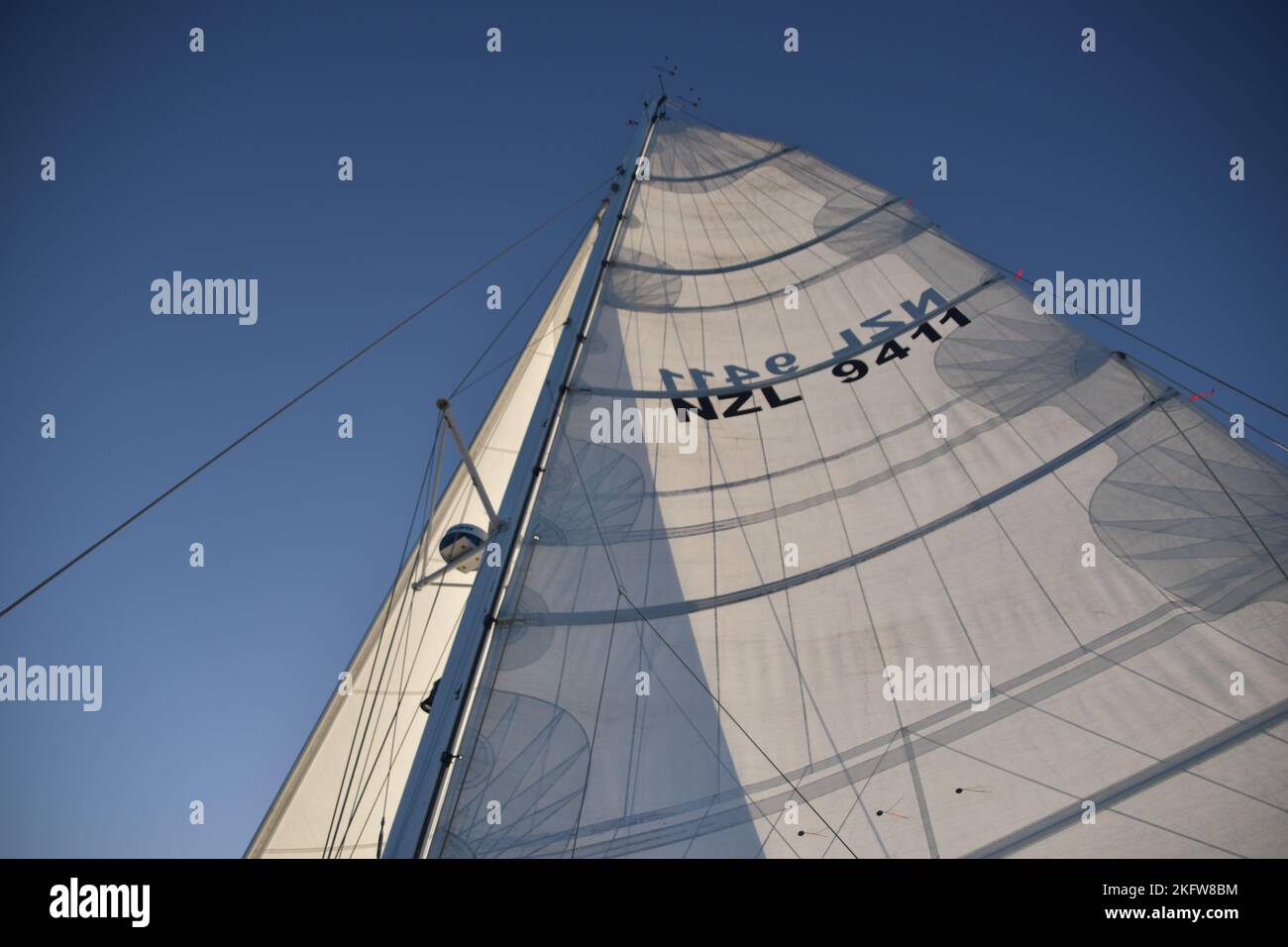 A low-angle of a white ship mainsail with a blue sky in the background ...