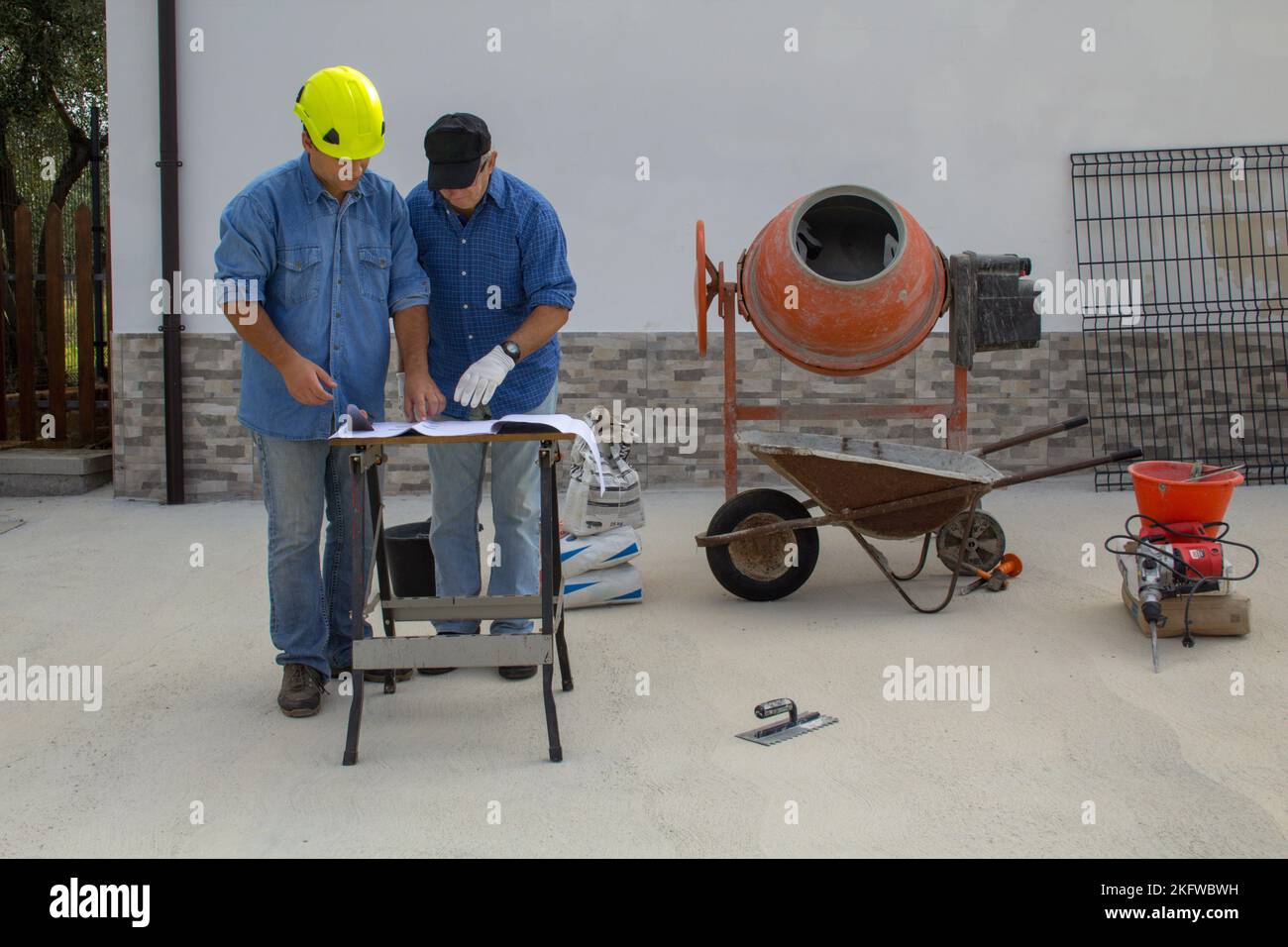 Image of an engineer and construction worker on a construction site as they consult the plan of ...
