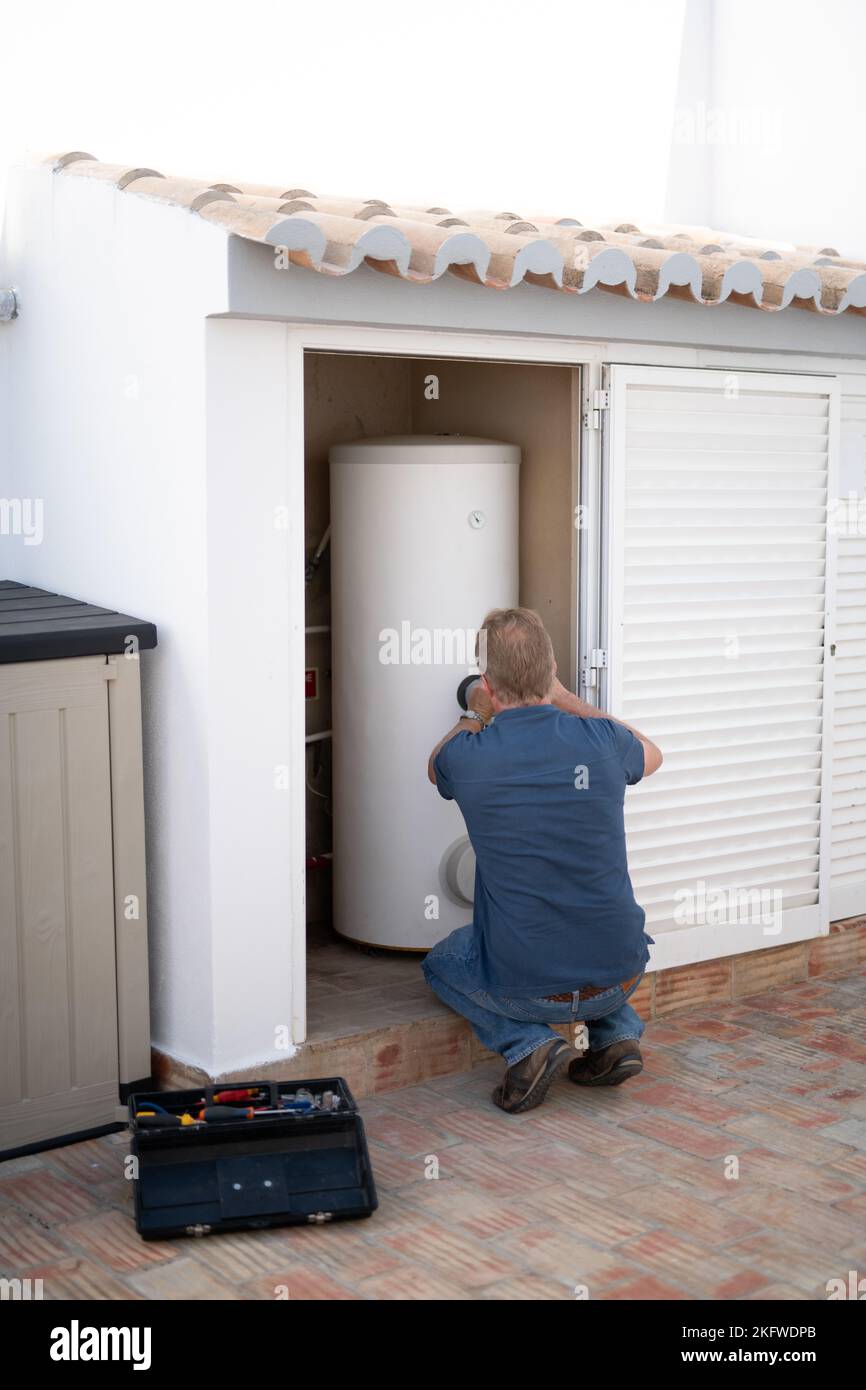 Man working on a domestic hot water tank Stock Photo - Alamy