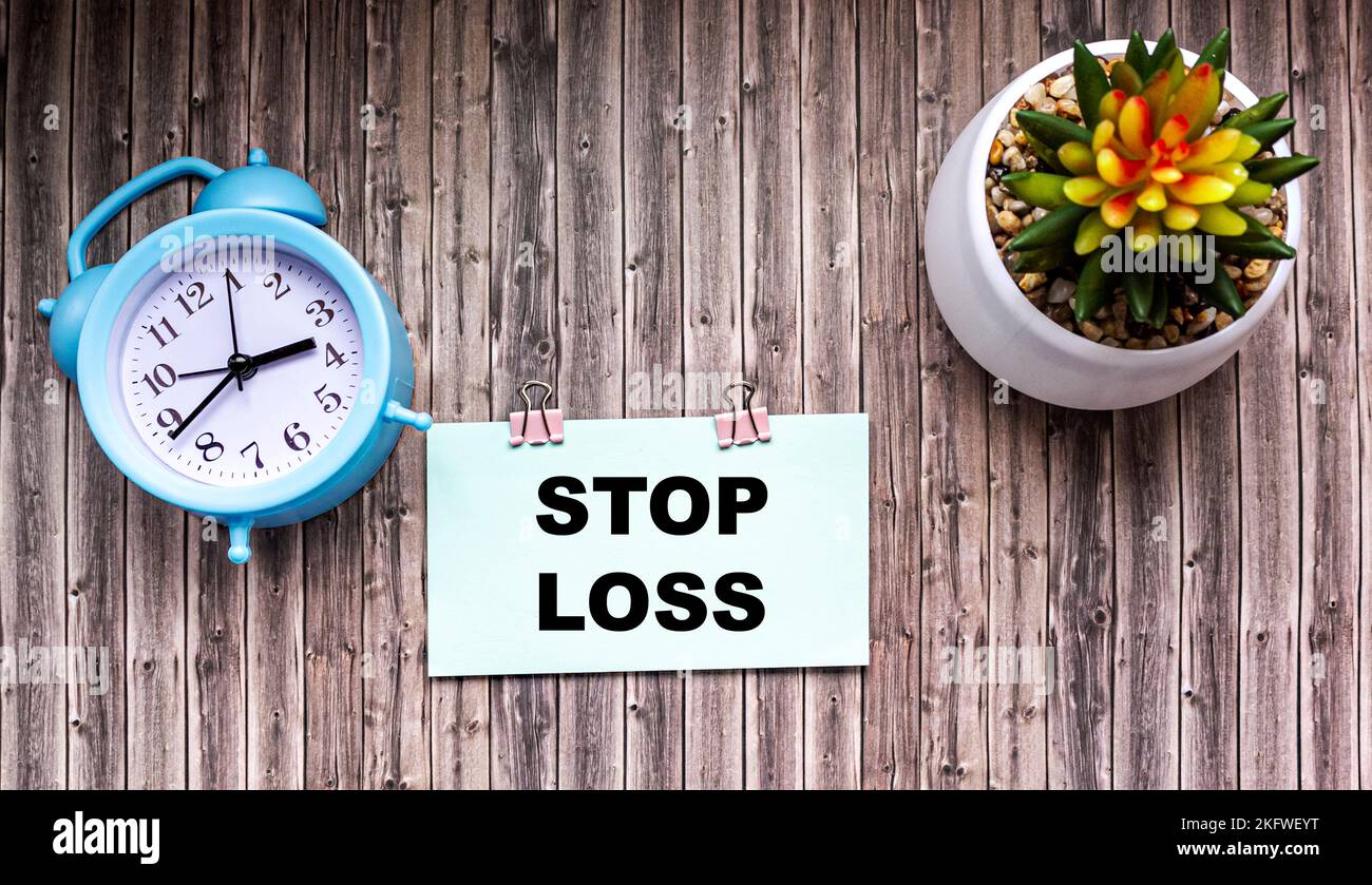 STOP LOSS. text on sticker and wooden background with clock and cactus ...