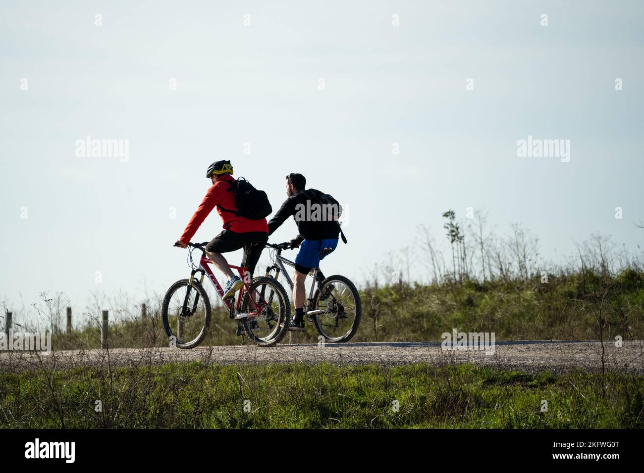 a pair of casual cyclists riding along across a country cycle path ...