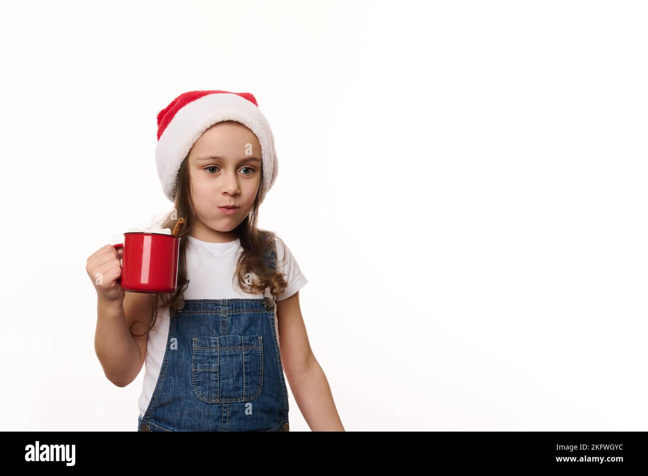 Mischievous funny baby girl in Santa hat, drinking hot cocoa drink and ...
