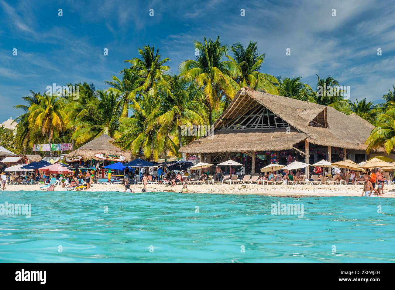 People sunbathing on the white sand beach with umbrellas, bungalow bar ...