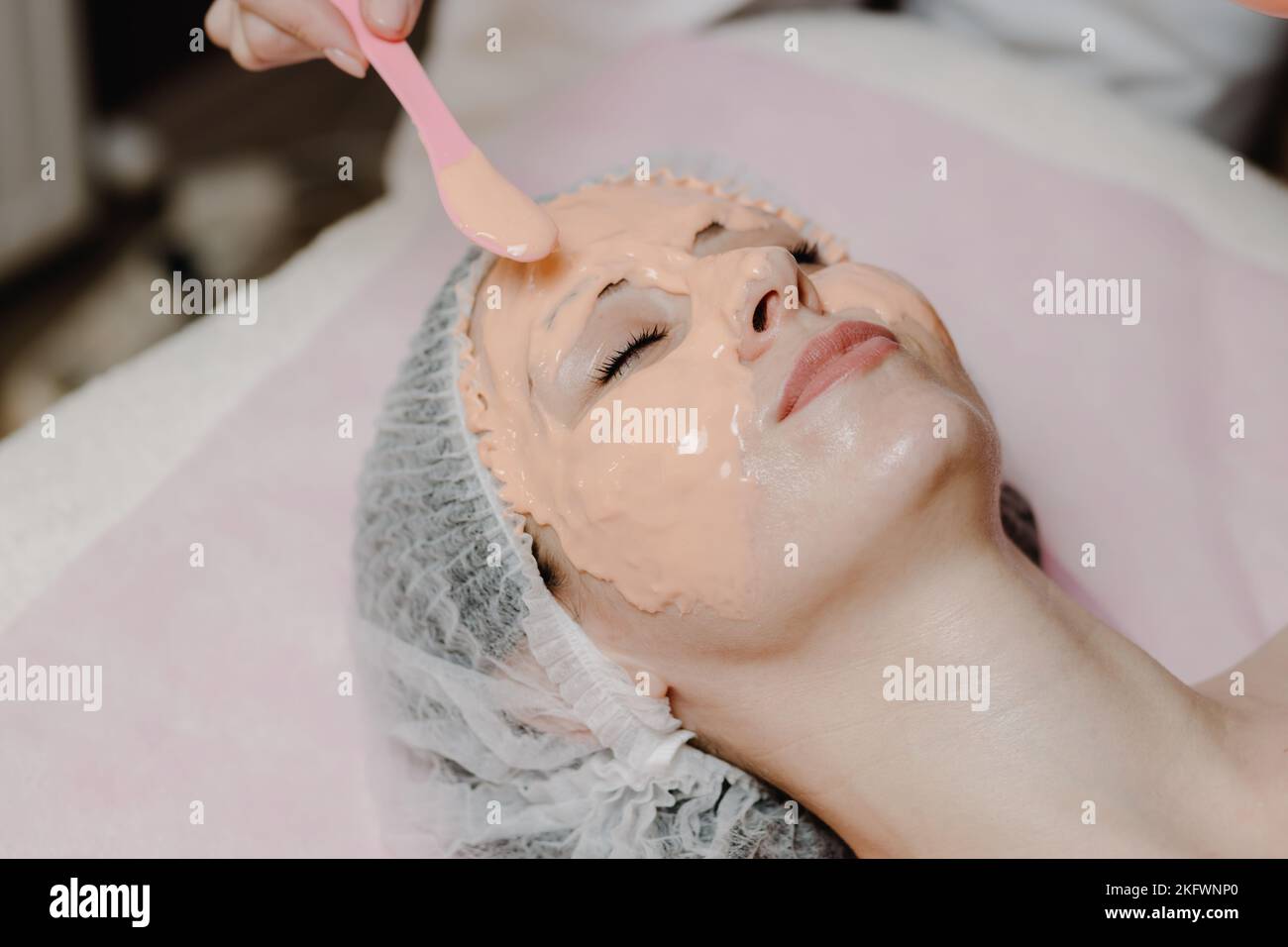 The process of applying a filling alginal mask to the face of a young ...