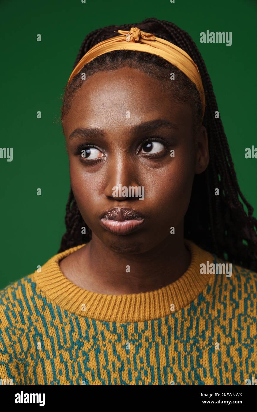 Young black woman with afro pigtails grimacing and looking aside ...