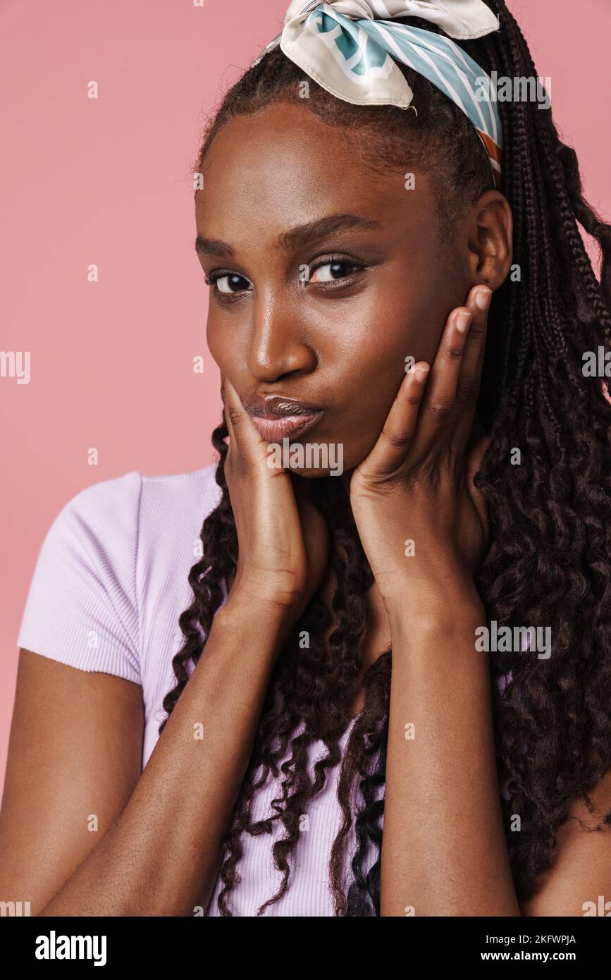 Young black woman with afro pigtails grimacing and looking at camera ...