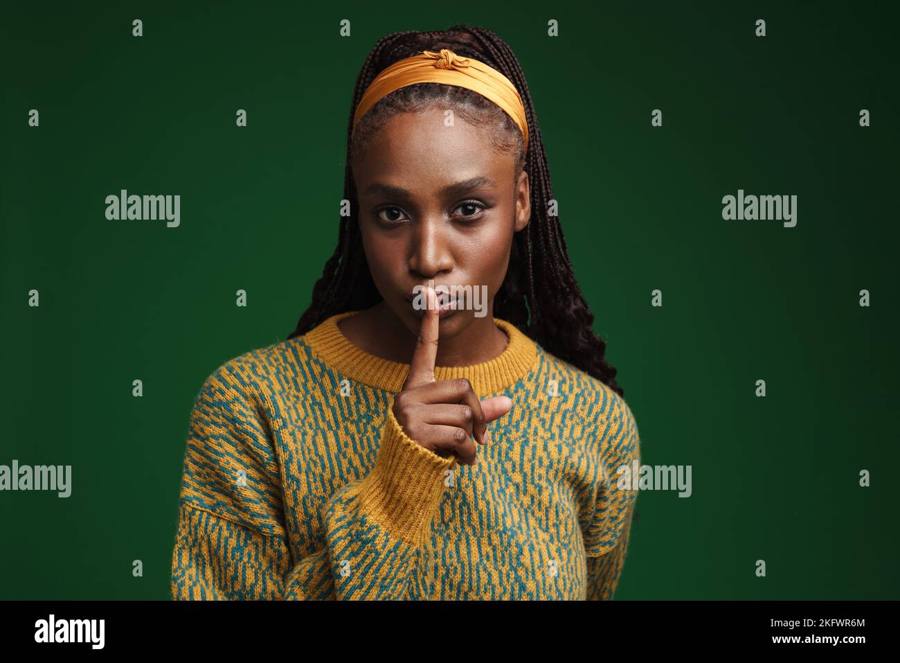 Young Black Woman Wearing Headband Showing Silence Gesture At Camera