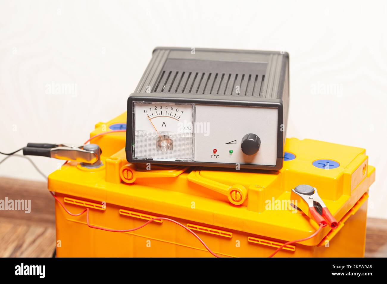 yellow car battery with car battery charger isolated on white ...