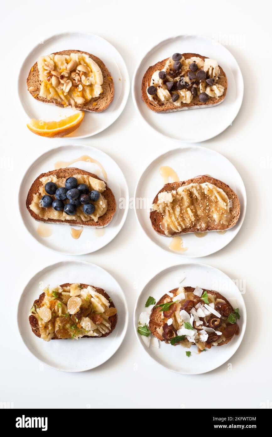 A vertical top-view of various healthy toasts with fruits in white ...