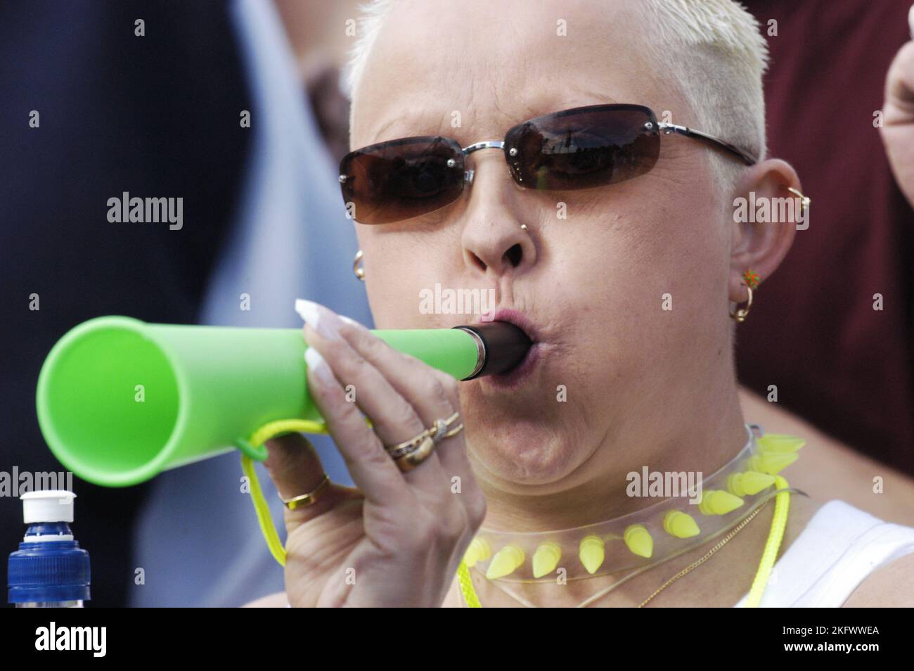 WOMAN CLUBBER, BLONDE BUZZCUT, BLOWING HORN, HOMELANDS 2003: A oman in ...