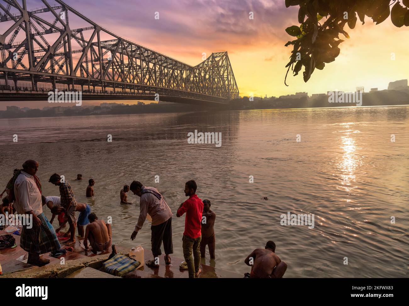 People bathing at the Ganges river bank at sunrise with view of ...