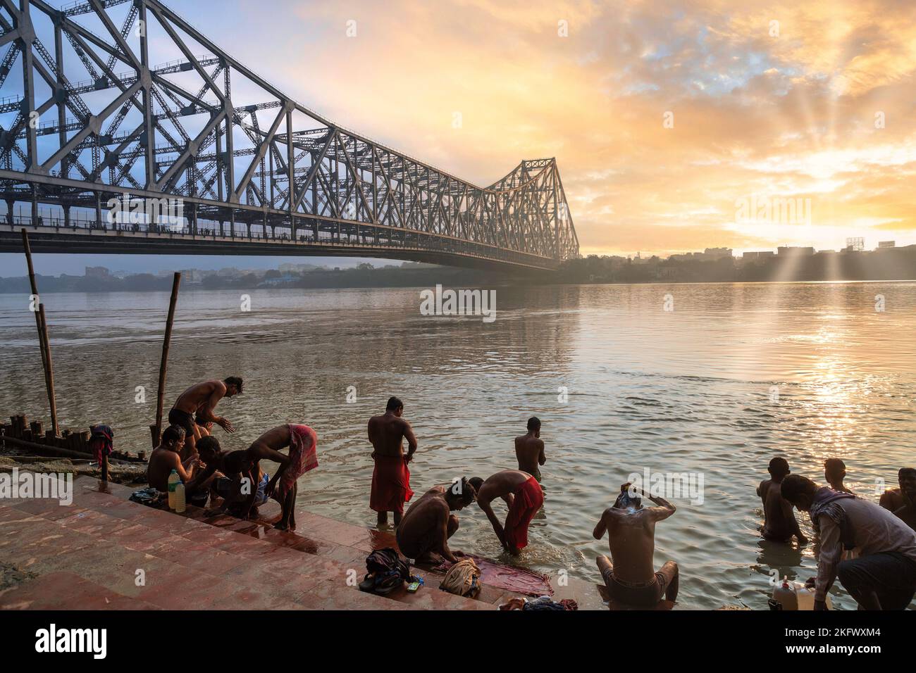 People bathing at the Ganges river bank at sunrise with view of ...