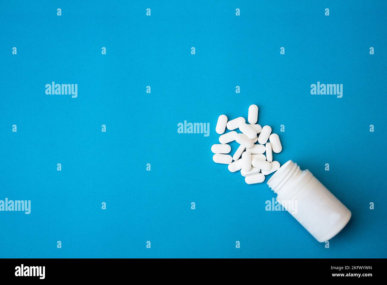 medicine white tablets and medicine bottle isolated on blue background ...