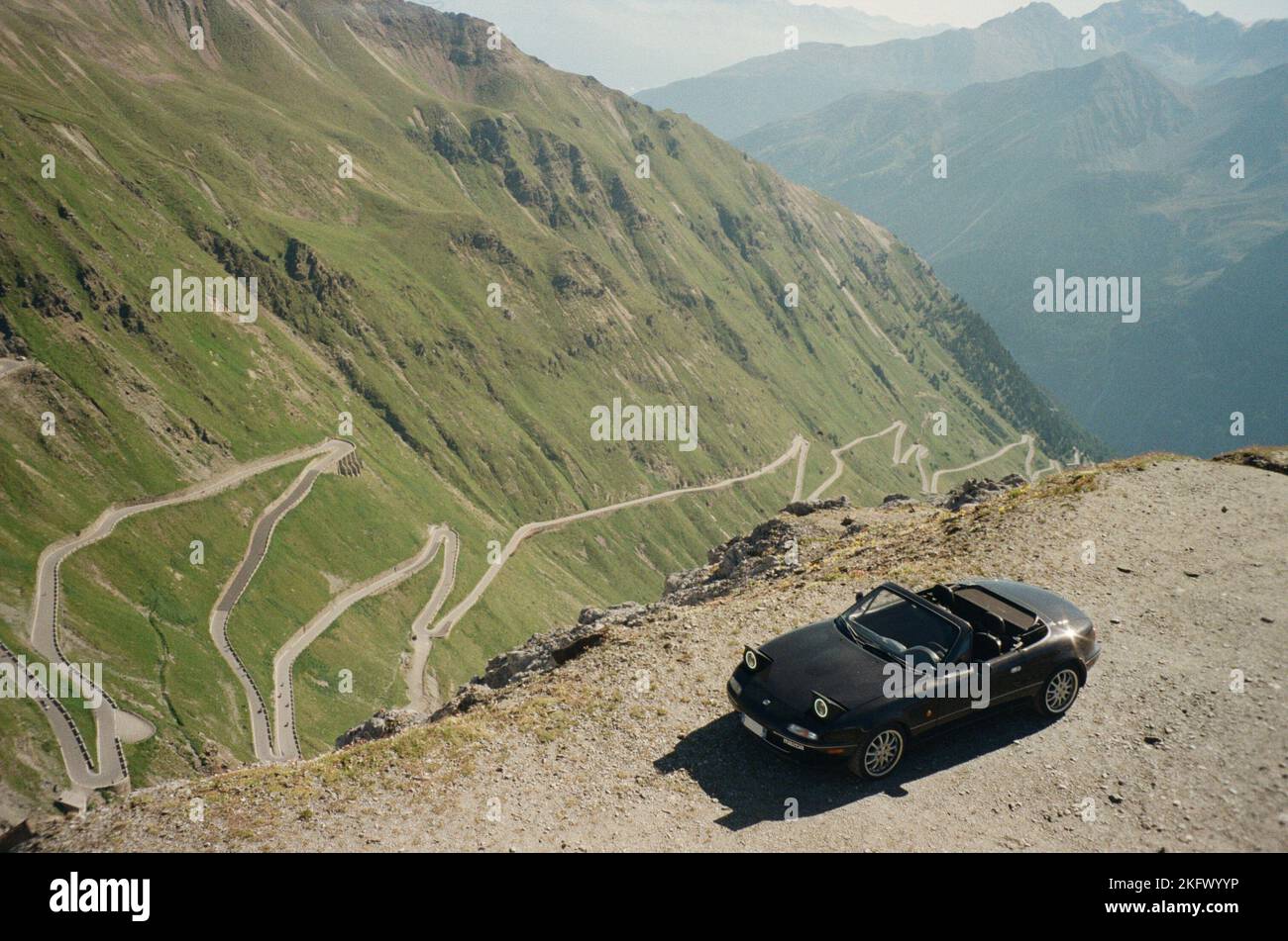 An aerial view of the black retro car on a high hill on a mountainous ...