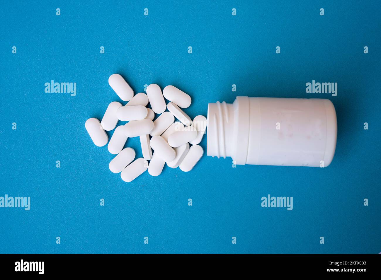 medicine white tablets and medicine bottle isolated on blue background ...