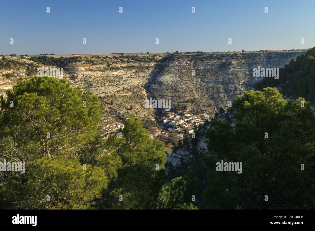 A high-angle of a sunlit valley with pine trees around and clear sunlit ...