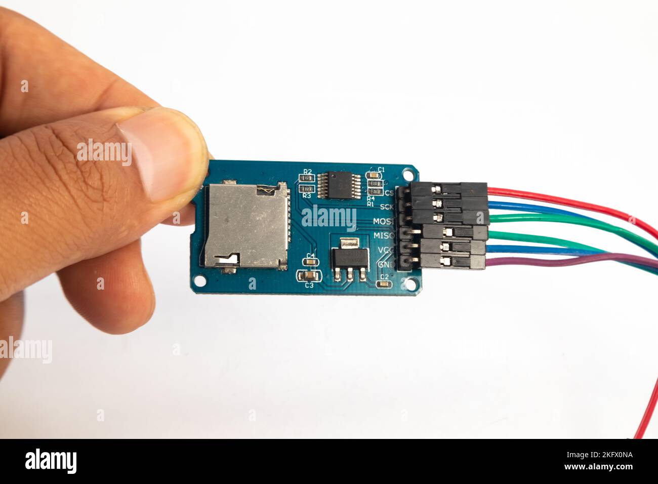 A microSD card reader module with its connecting cable is held in the ...