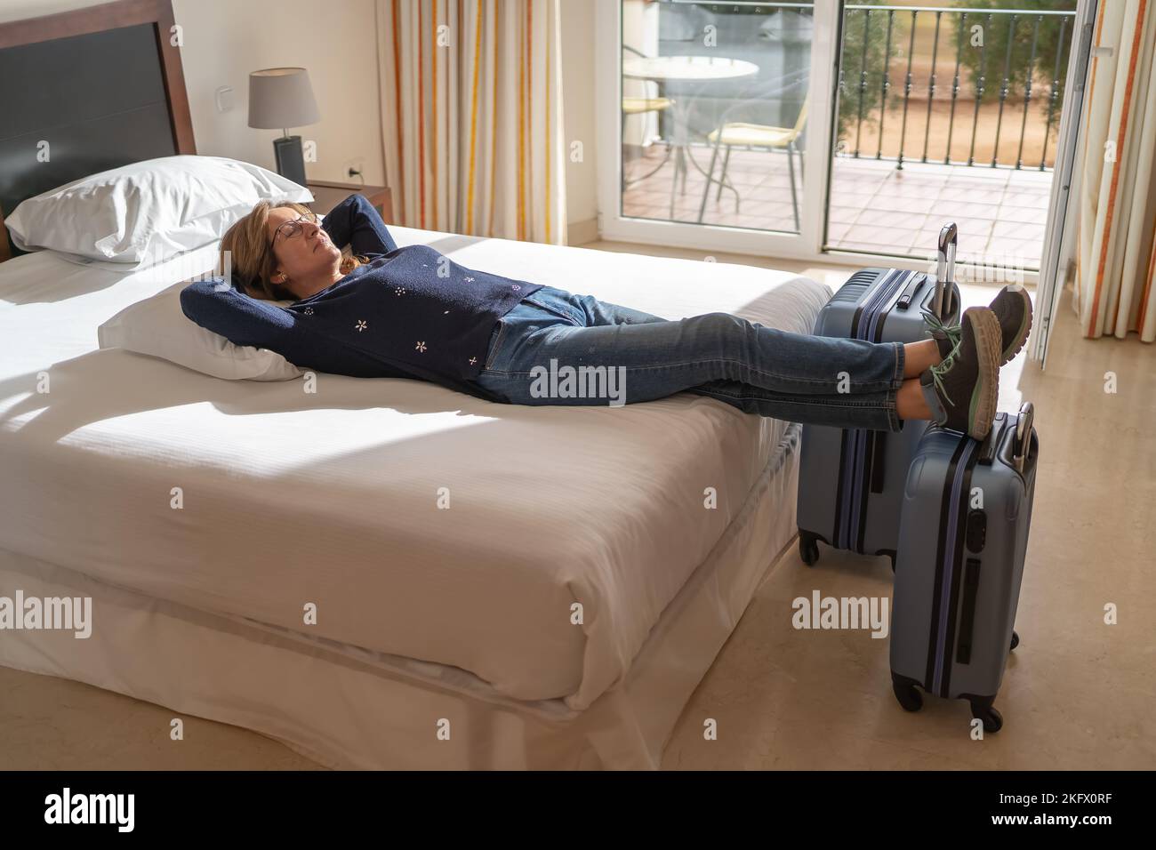 Woman lying in bed in a posture of relaxation and rest on arrival at ...