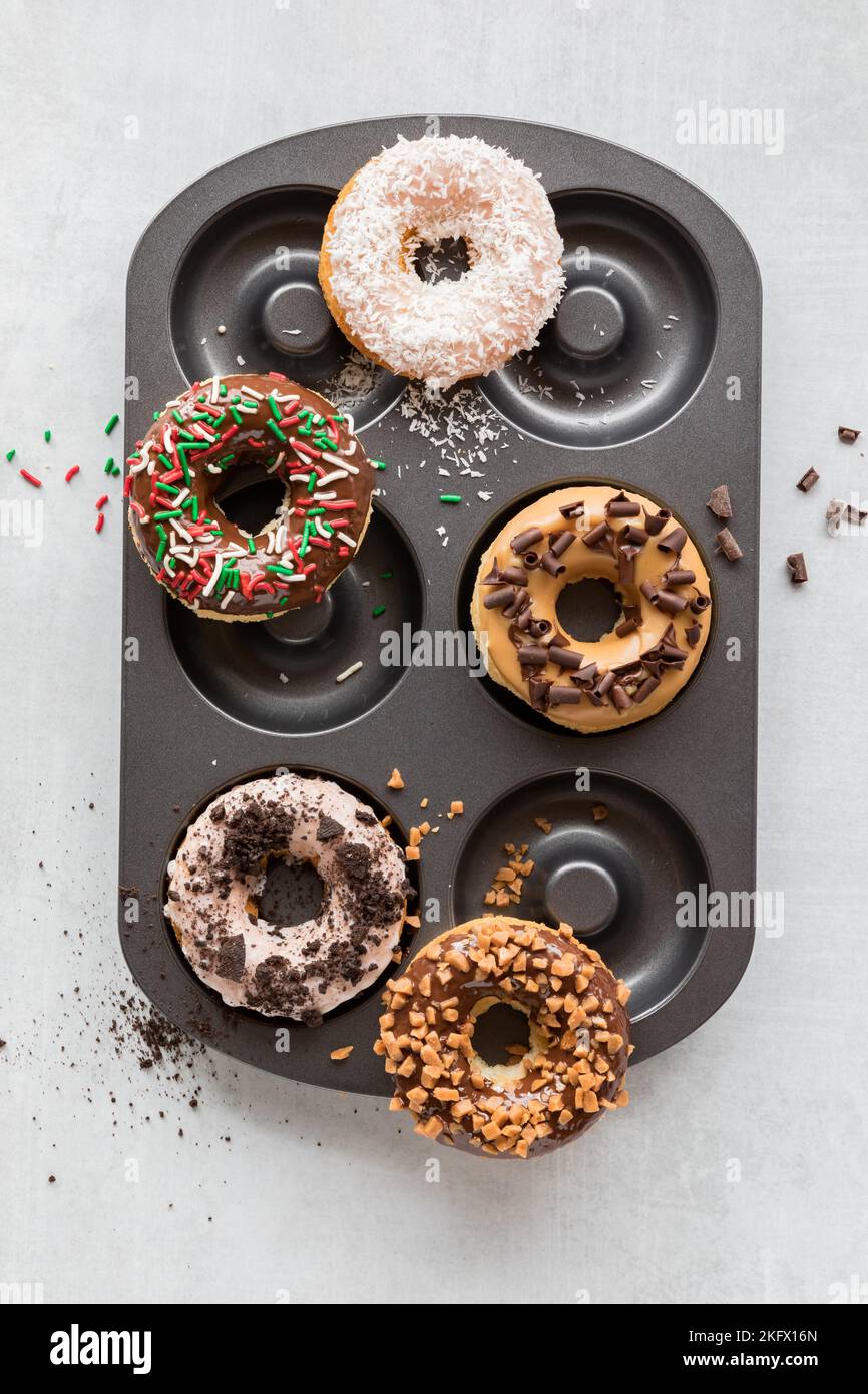 A donut pan topped with various homemade donuts with different toppings ...
