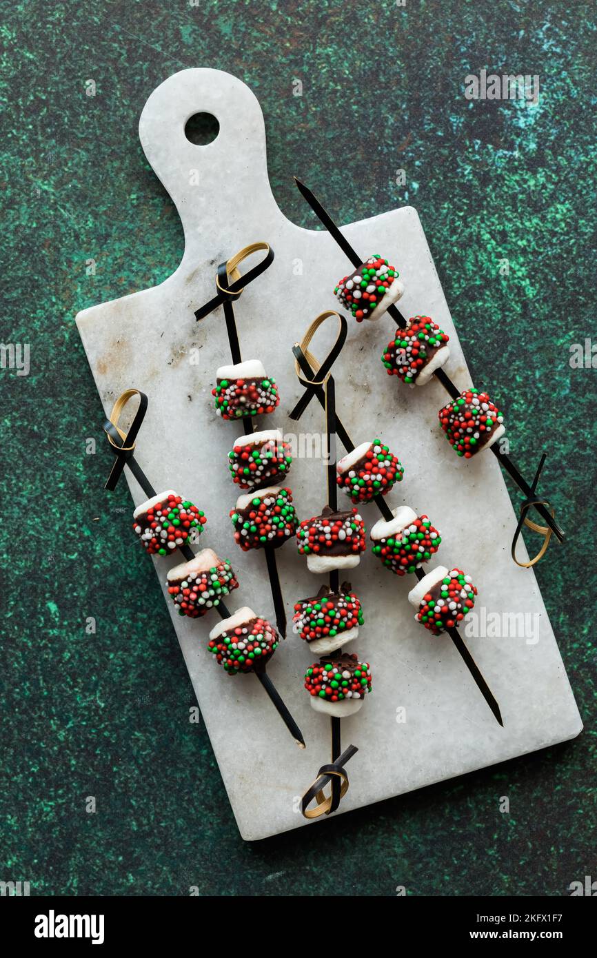 A small marble slab topped with chocolate dipped picks covered in ...