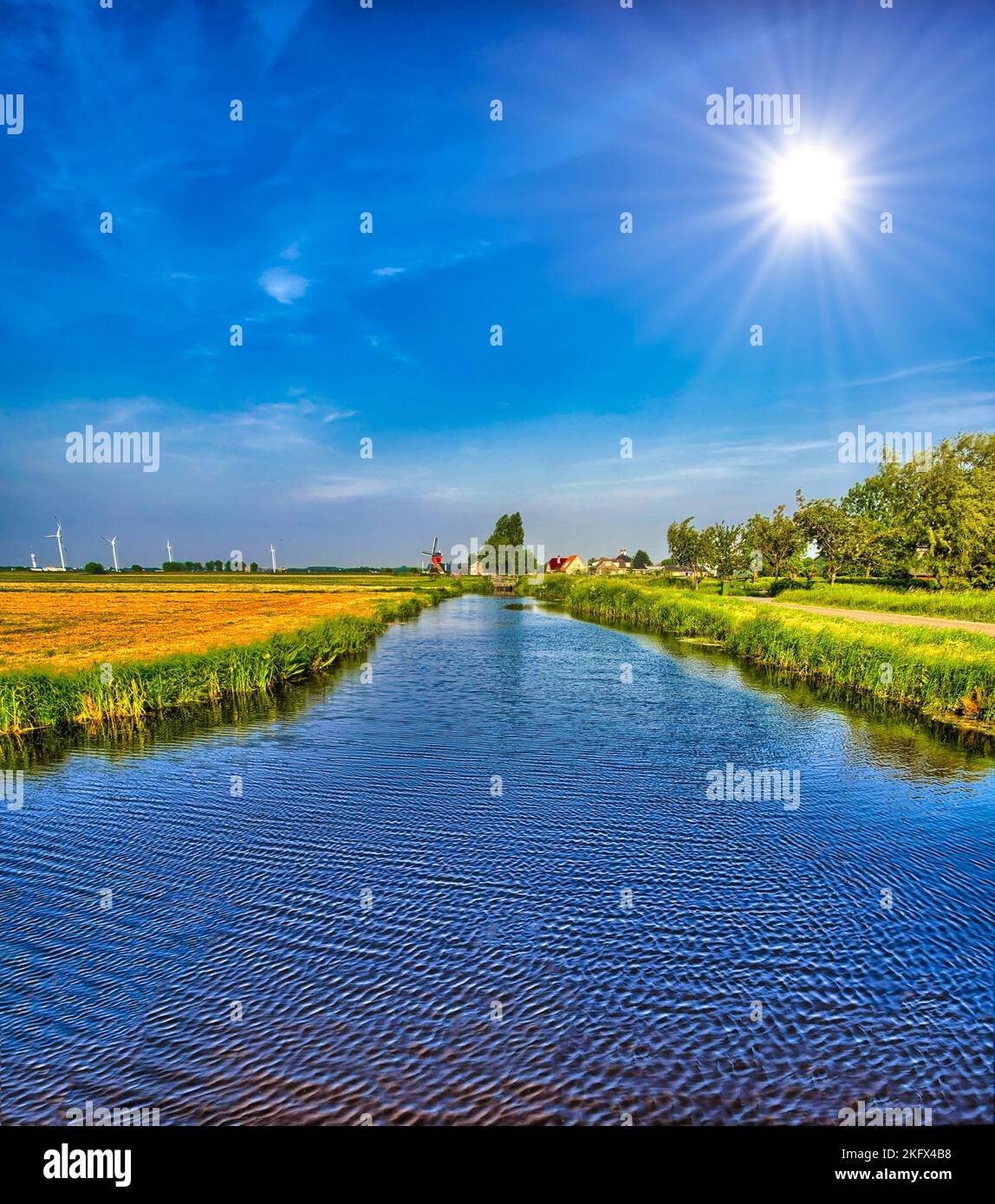 Dutch landscape with a canal and grass fields with mirror reflection in ...