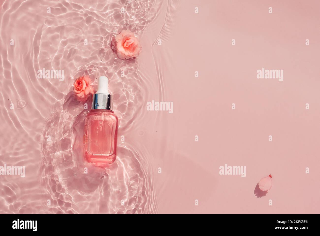 Pink transparent bottle with rose oil, serum on a water background with ...