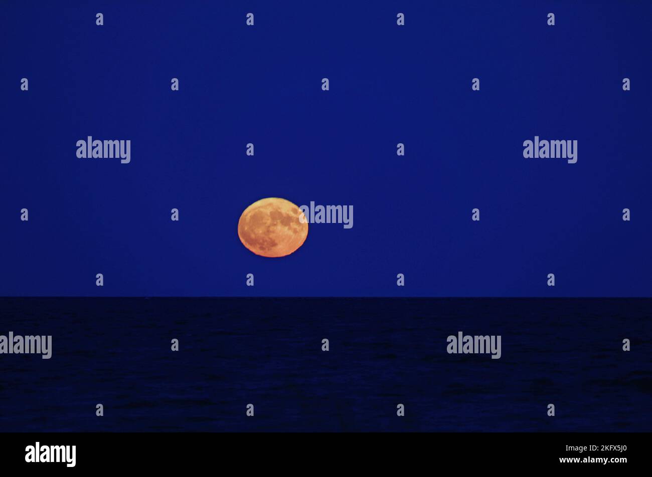 red full moon over the calm evening sea Stock Photo - Alamy