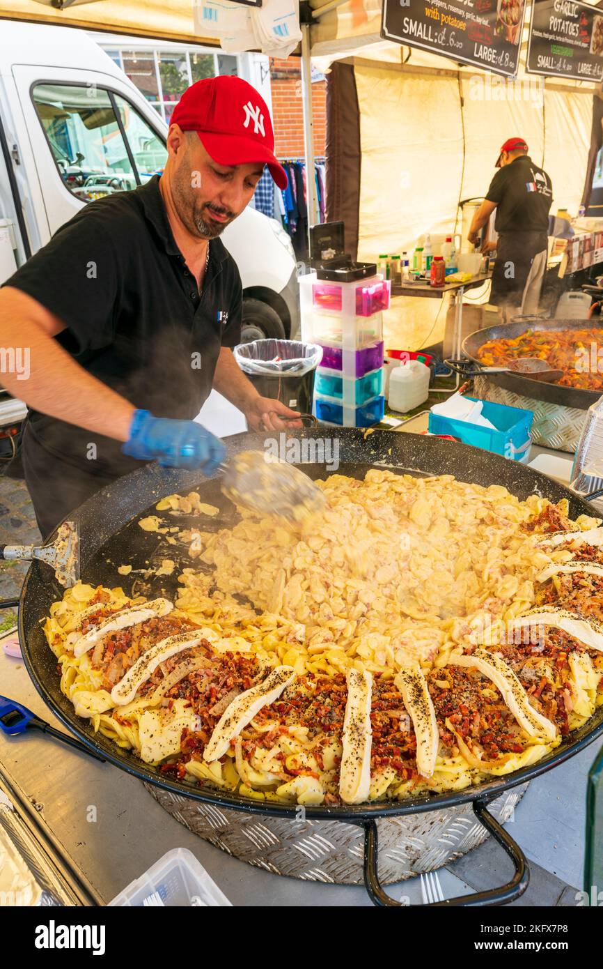 Close up a man stirring a large skillet pan full of steaming hot ...