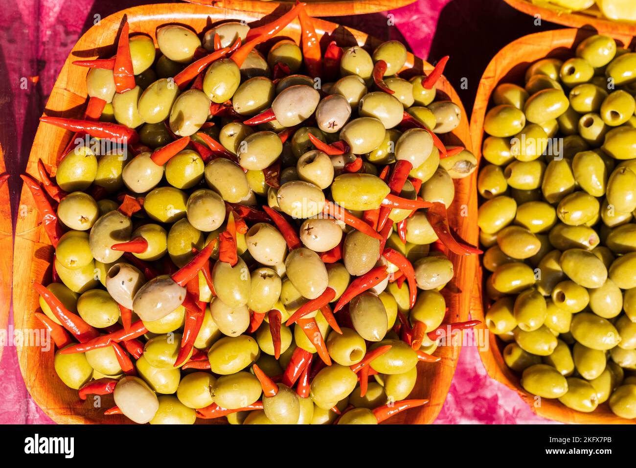 Overhead close up of a basket of green olives in the sunshine on a ...