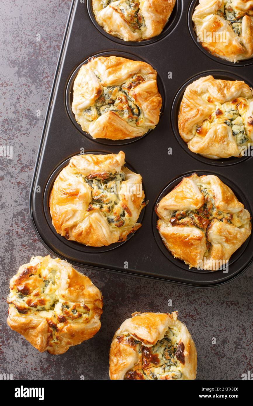 Puff pastry muffins stuffed with spinach and feta cheese close-up in a ...