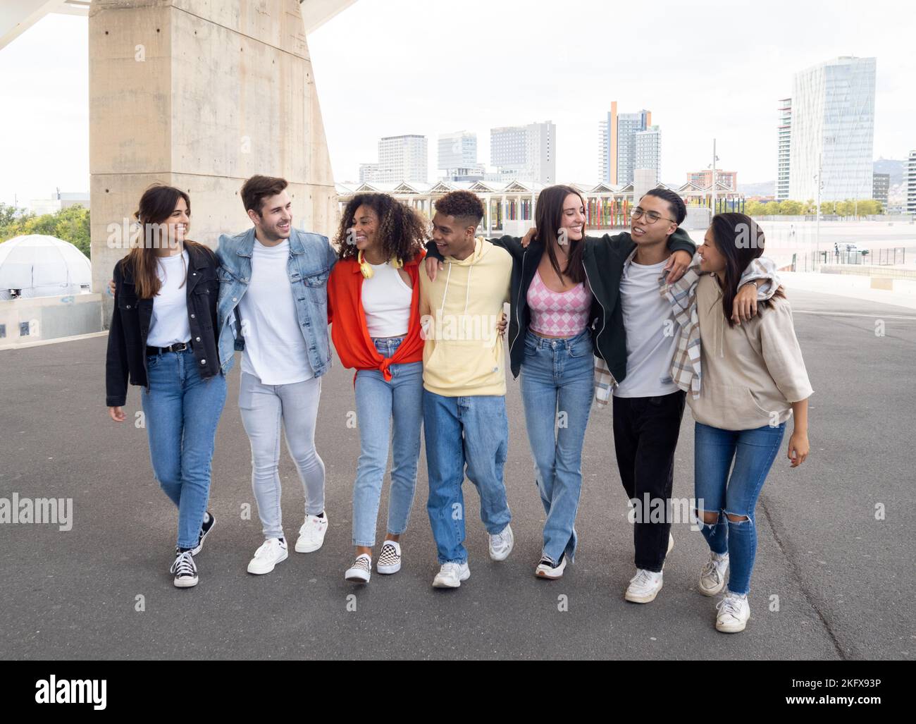 Group of multiethnic young friends walking through the city laughing ...