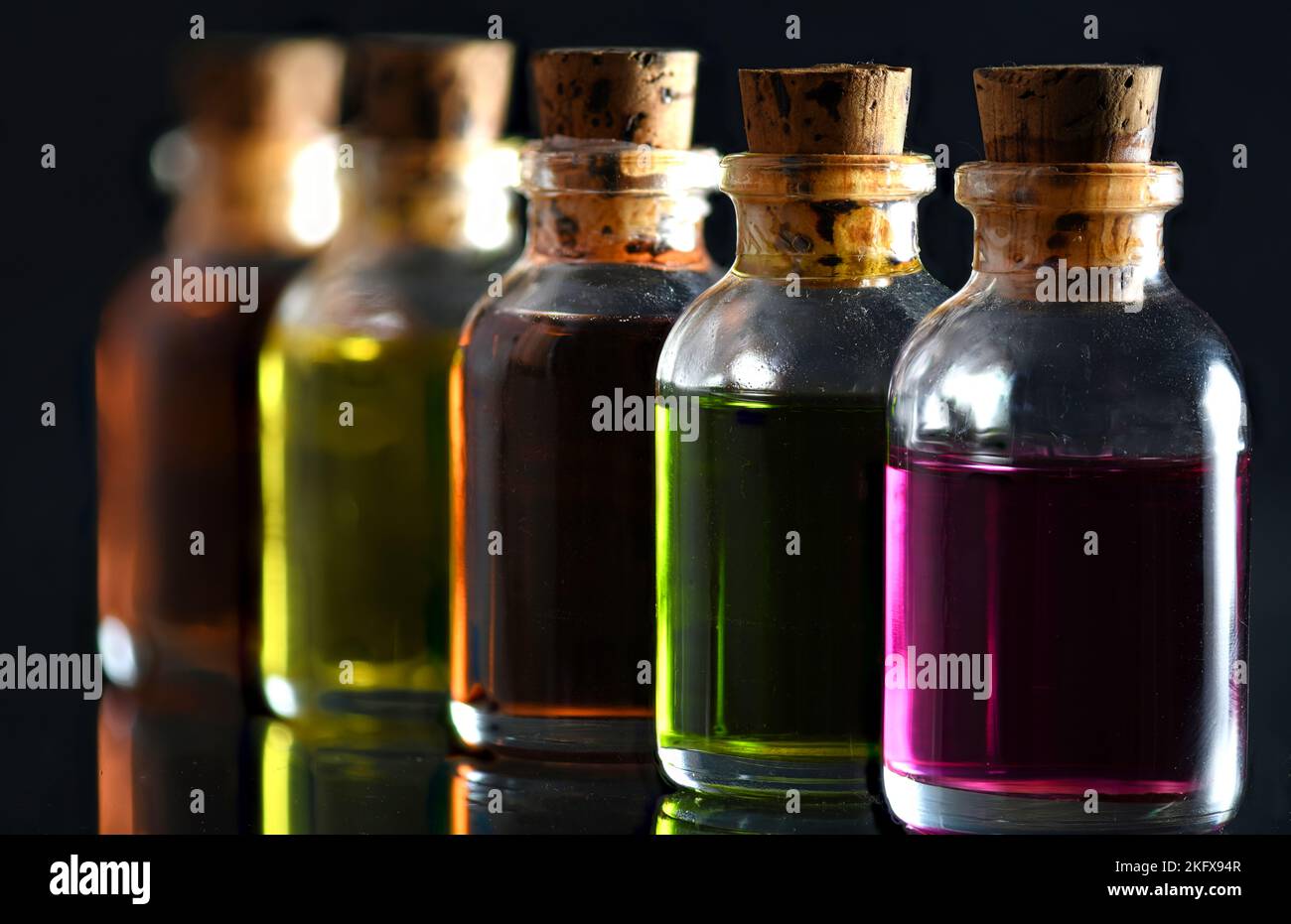 Colored Oil bottles on a black background Stock Photo - Alamy