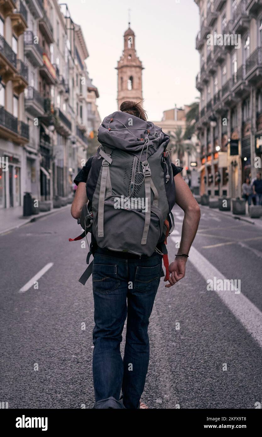 young caucasian traveler man running along the asphalt of a city street ...