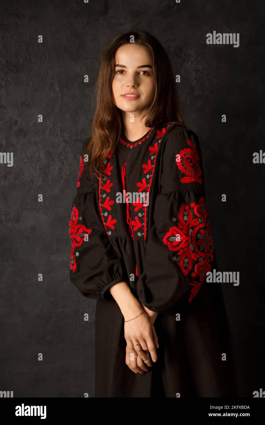A beautiful Ukrainian woman in a black embroidered dress on a dark ...