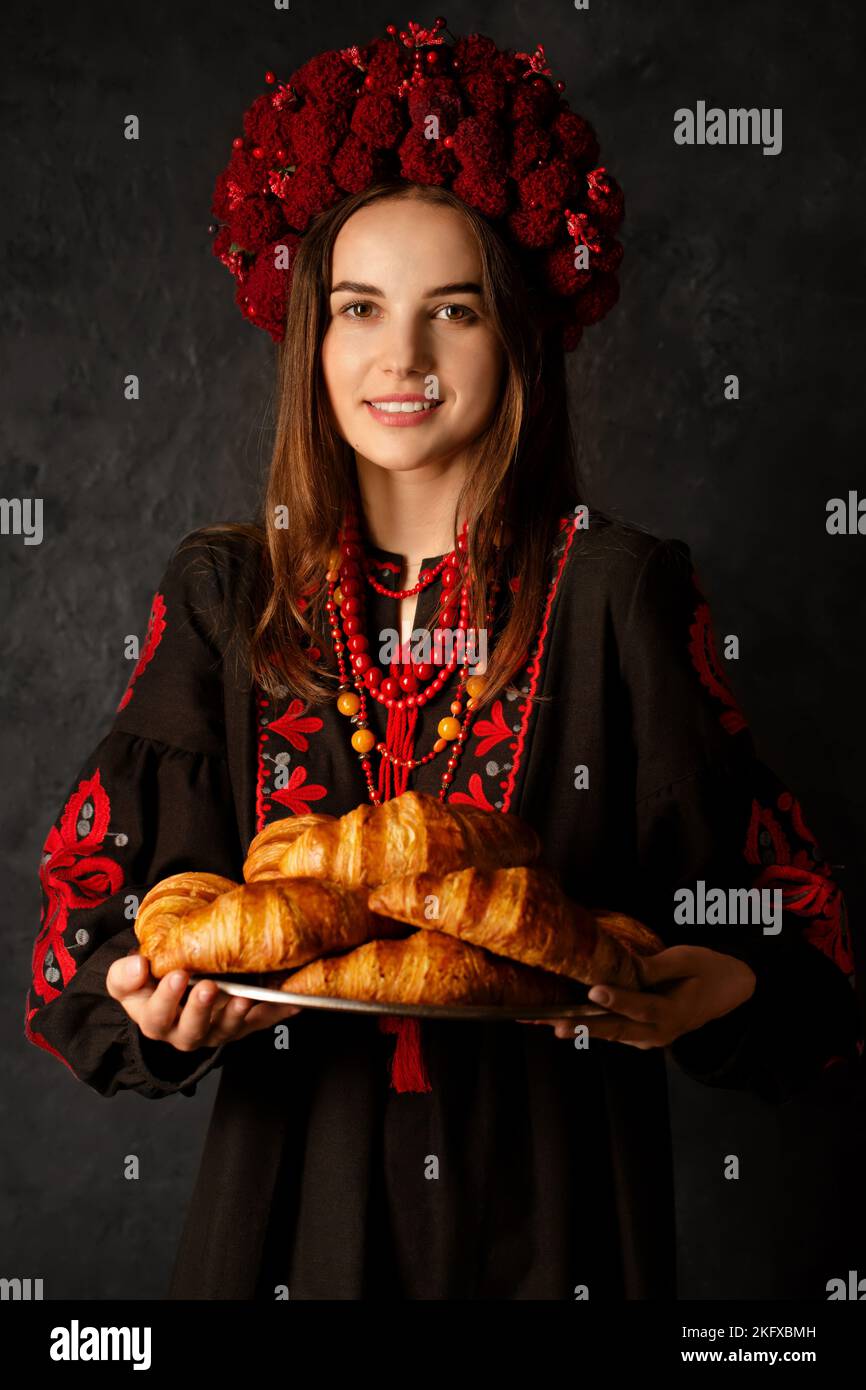 Ukrainian woman in national dress holds a tray with rosy croissants on ...