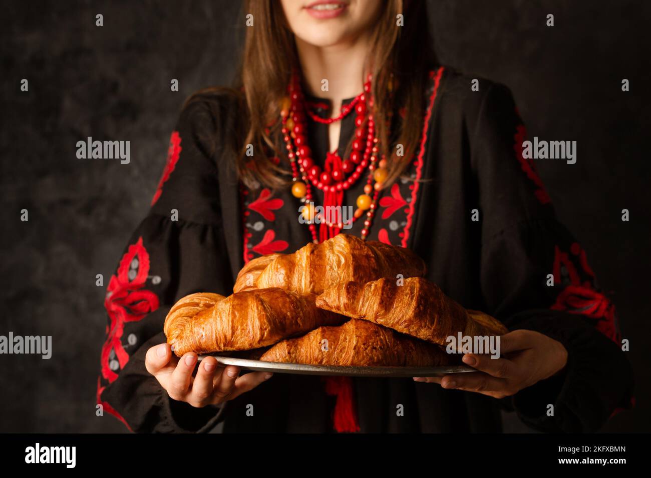 Ukrainian woman in national dress holds a tray with rosy croissants on ...
