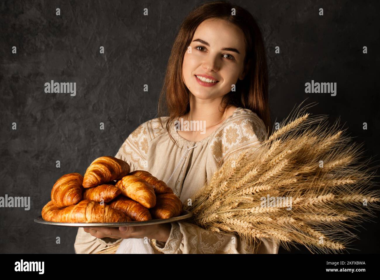 Ukrainian woman in national dress holds a tray with rosy croissants on ...