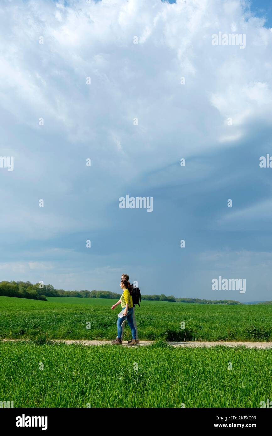 Couple of hikers walking on a small countryside road and holding a ...