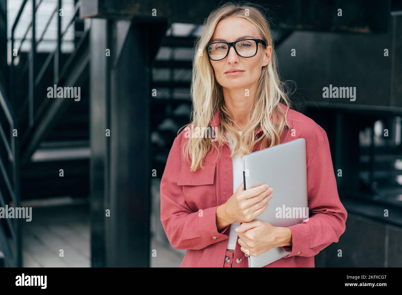 Elegant business woman stands and holds a laptop Stock Photo - Alamy