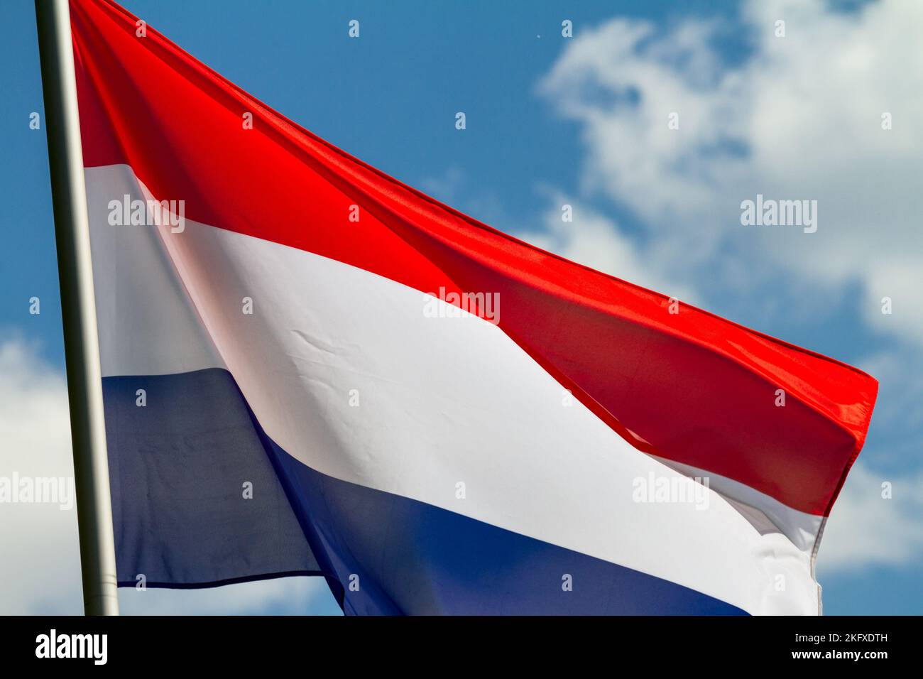 Flag of the Netherlands waving in the wind on flagpole against the sky ...
