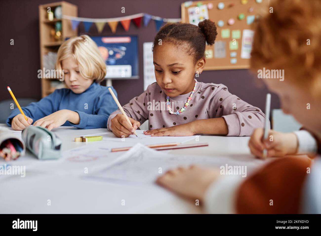 Cute African American learner of primary school drawing with crayons ...