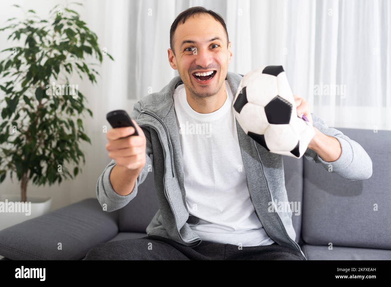 Portrait of excited young guy watching football match, raising clenched ...
