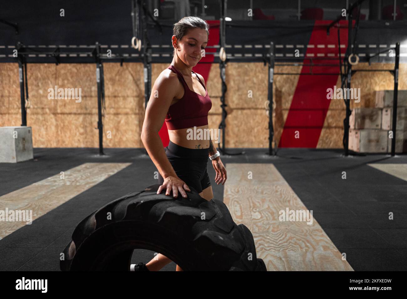 caucasian girl athlete standing smiling rolling a big crossfit tractor ...