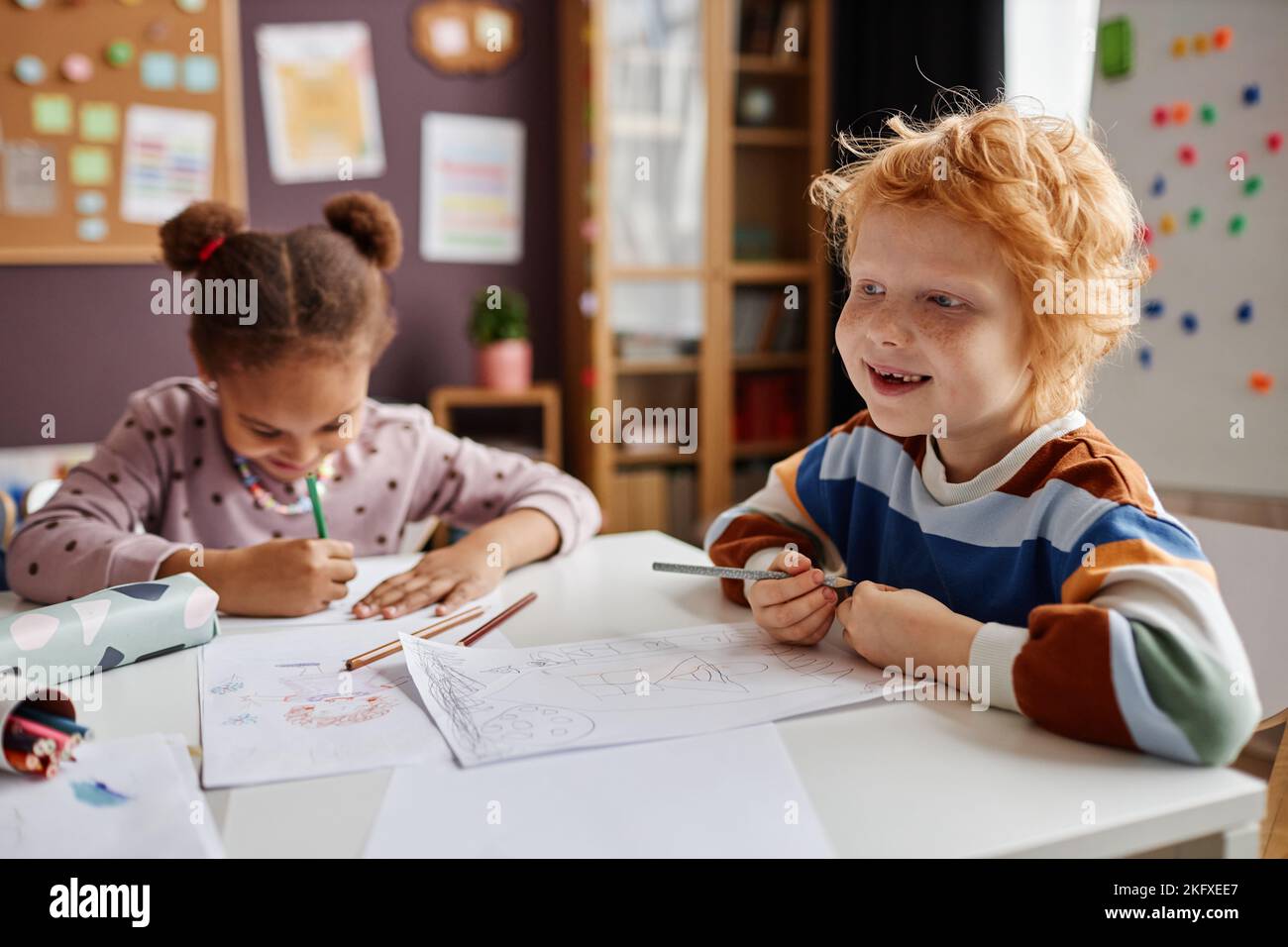 Cheerful cute learner of kindergarten with freckles and red hair ...