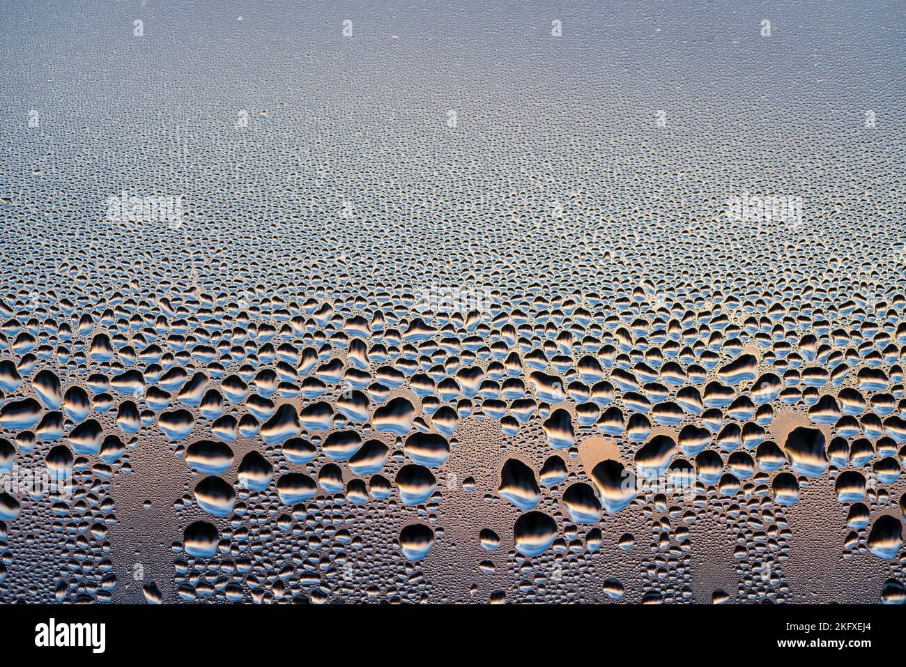 condensation from a drop of water on a window glass pane during dawn ...