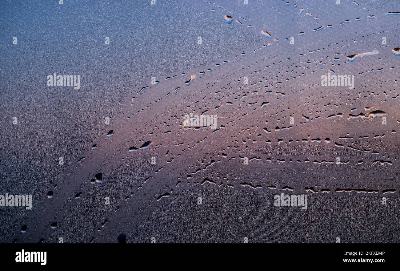 condensation from a drop of water on a window glass pane during dawn ...