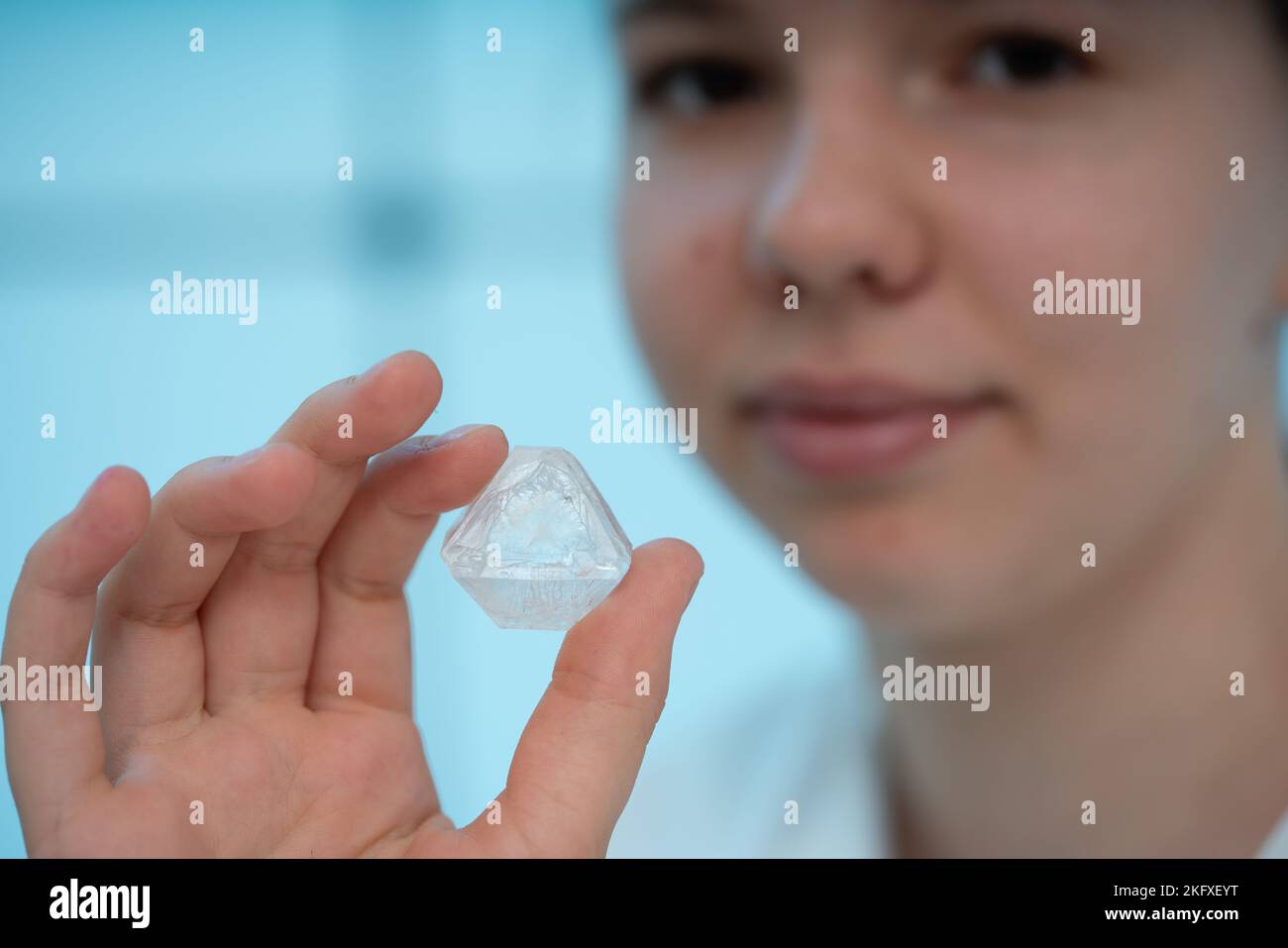a young woman holds in her hands a natural mineral crystal of a ...
